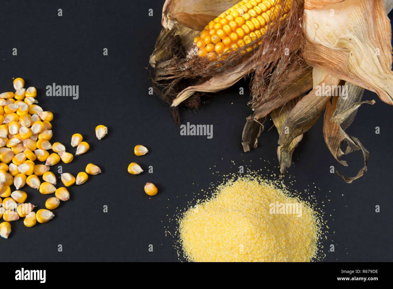 a corncob, corn grains and flour on a black surface Stock Photo - Alamy