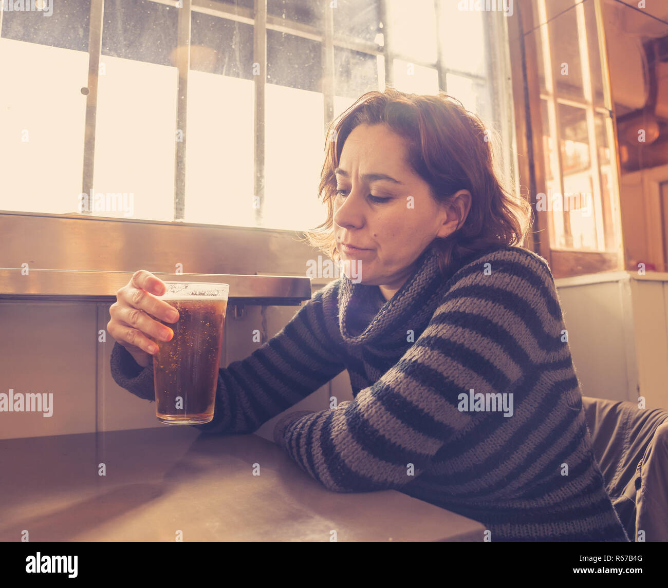 Portrait of a attractive latin woman drinking beer in a bar pub feeling ...