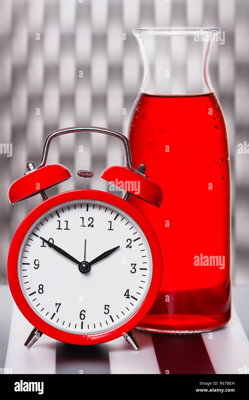 Vintage red clock and carafe of wine on striped and checkered black and ...