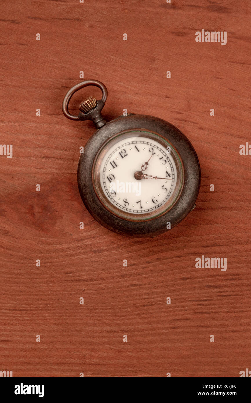 A photo of an old watch, shot from the top on a dark rustic wooden ...
