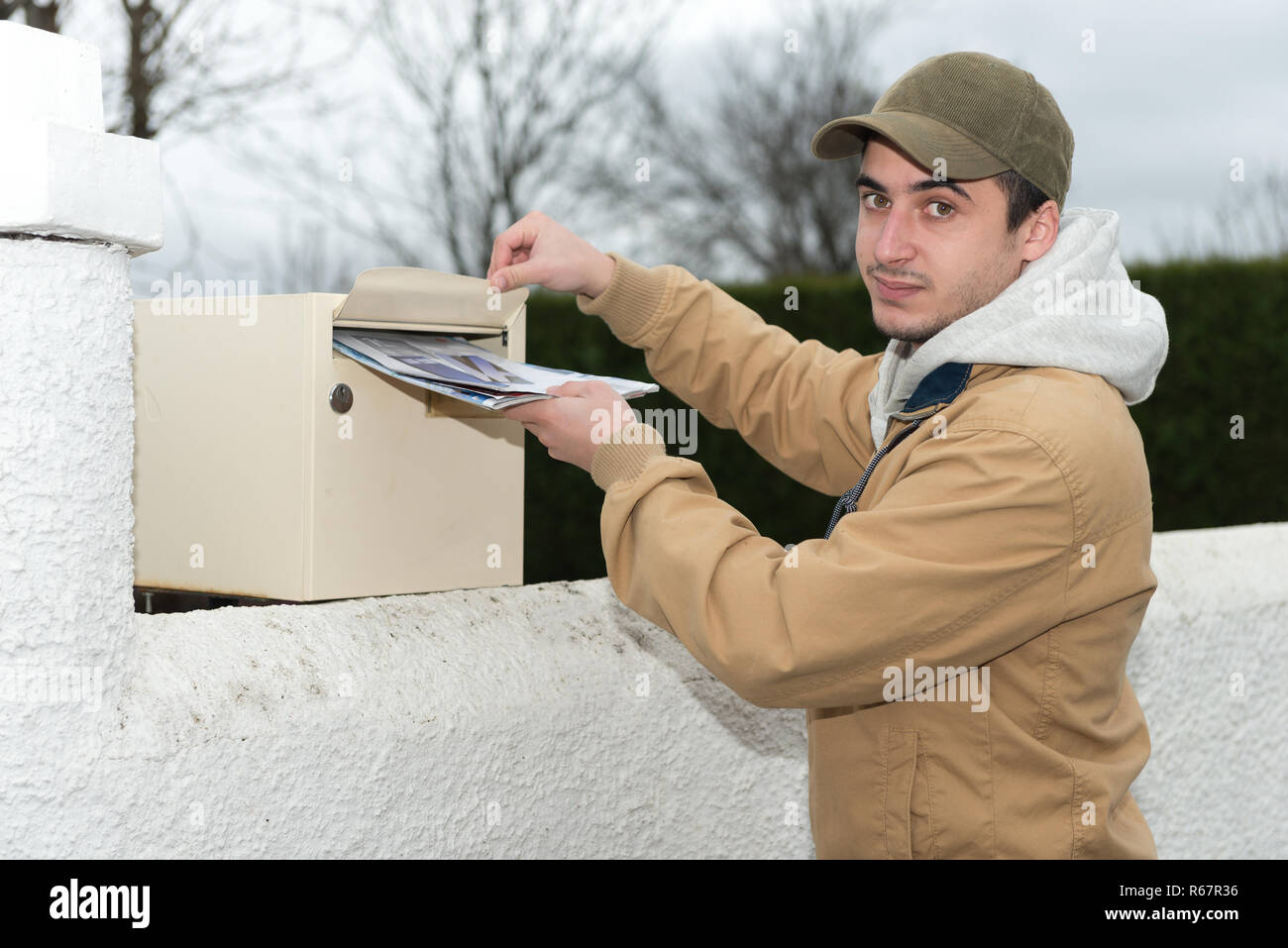 man putting newspaper from the mailbox Stock Photo - Alamy