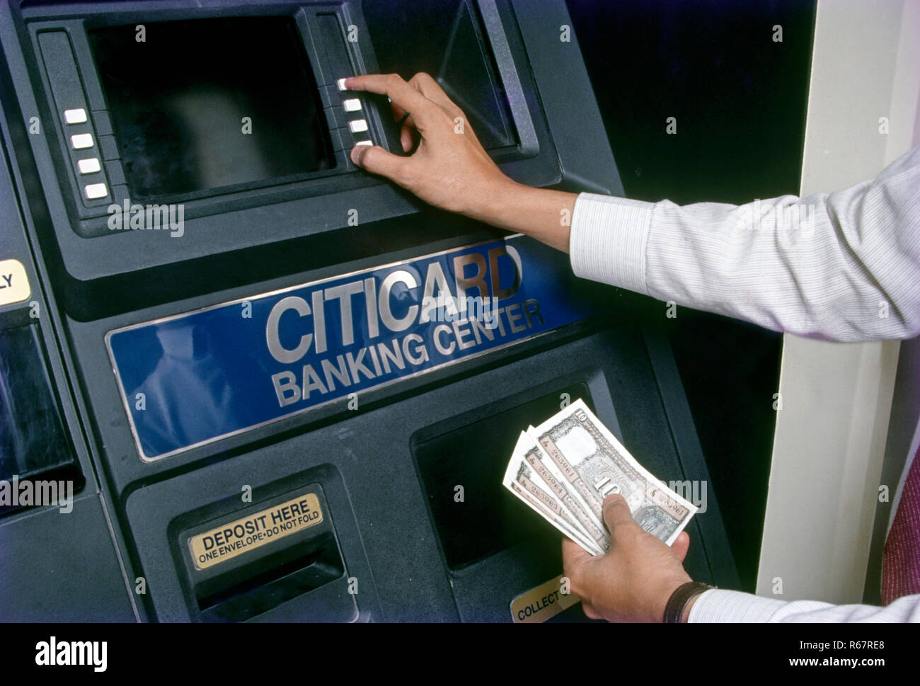 Close up of hand holding Ten Rupees Notes and push buttons of ATM ...