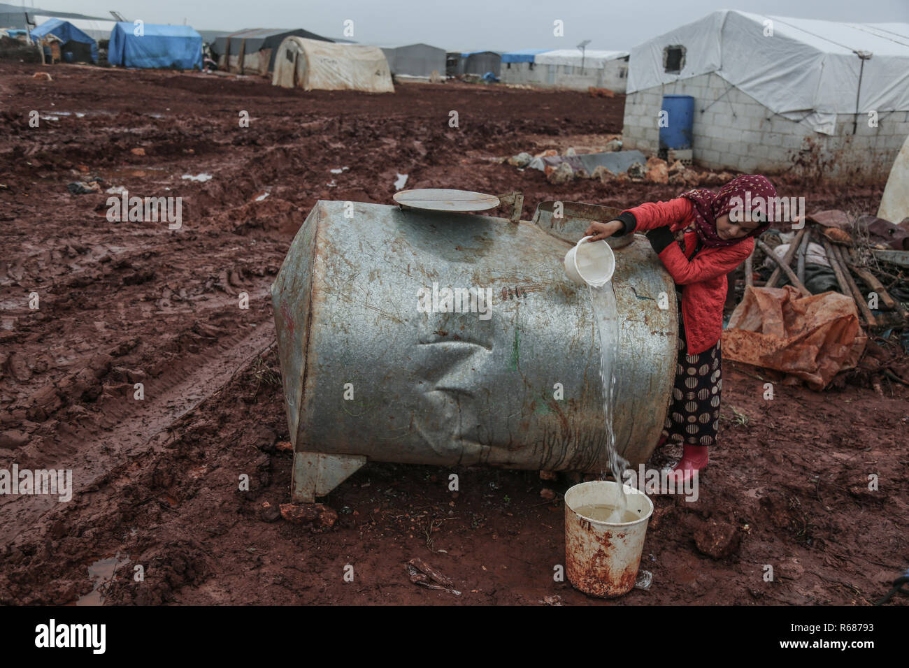 Idlib, Syria. 04th Dec, 2018. A displaced Syrian girl fills water from ...