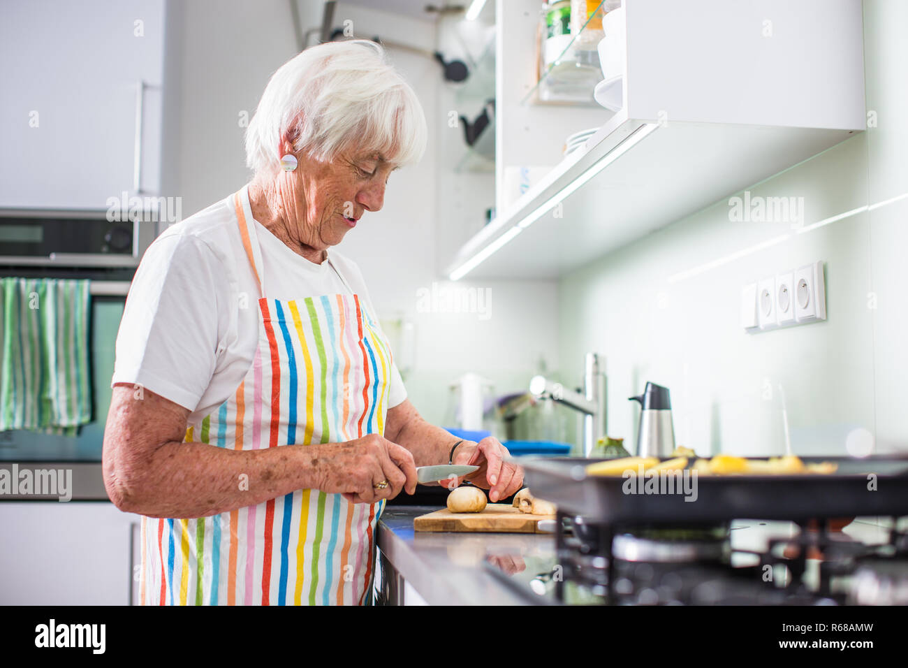 Senior woman cooking in the kitchen - eating and cooking healthy for ...
