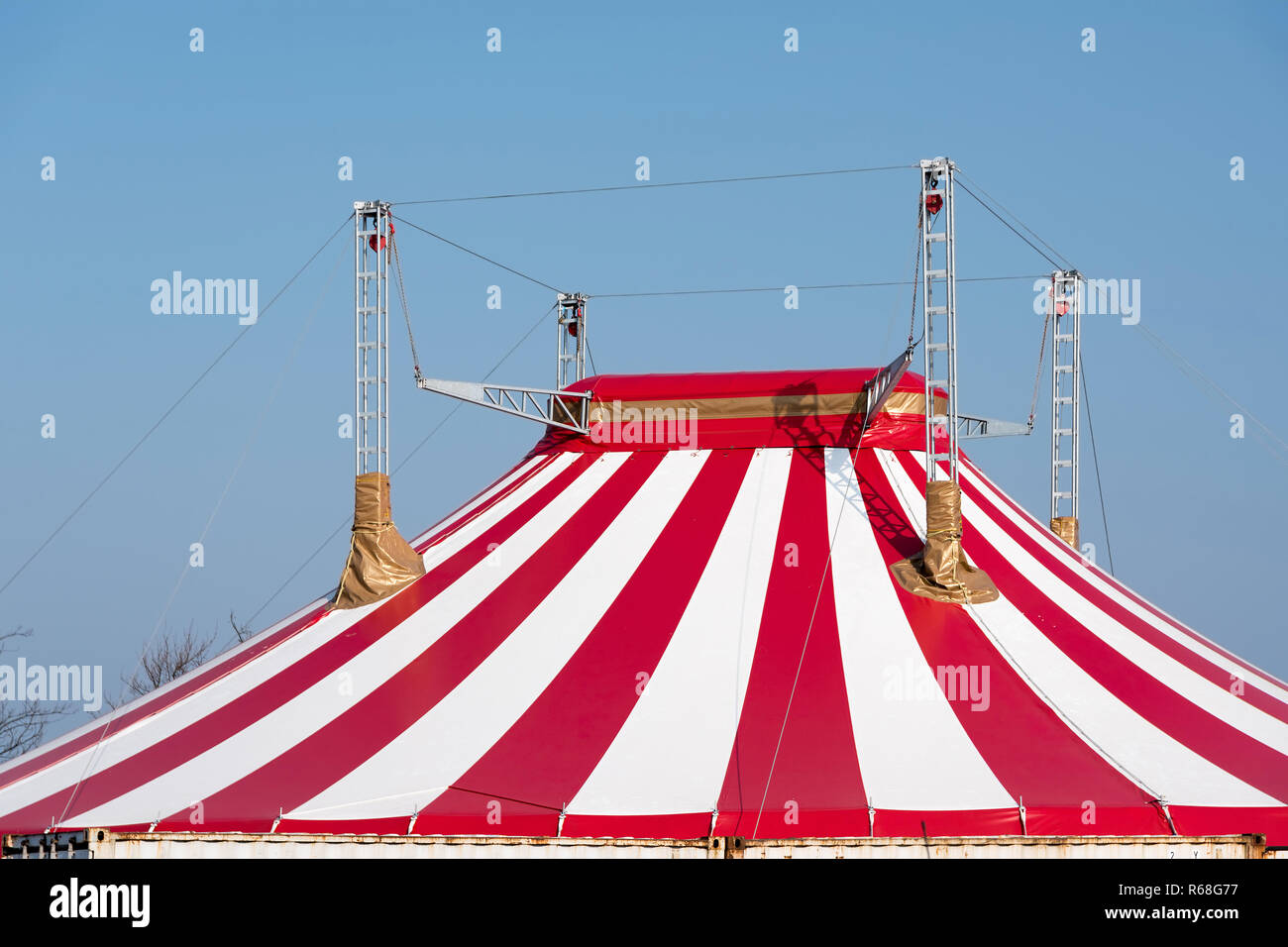 roof of a circus tent with red and white stripes and four masts against ...