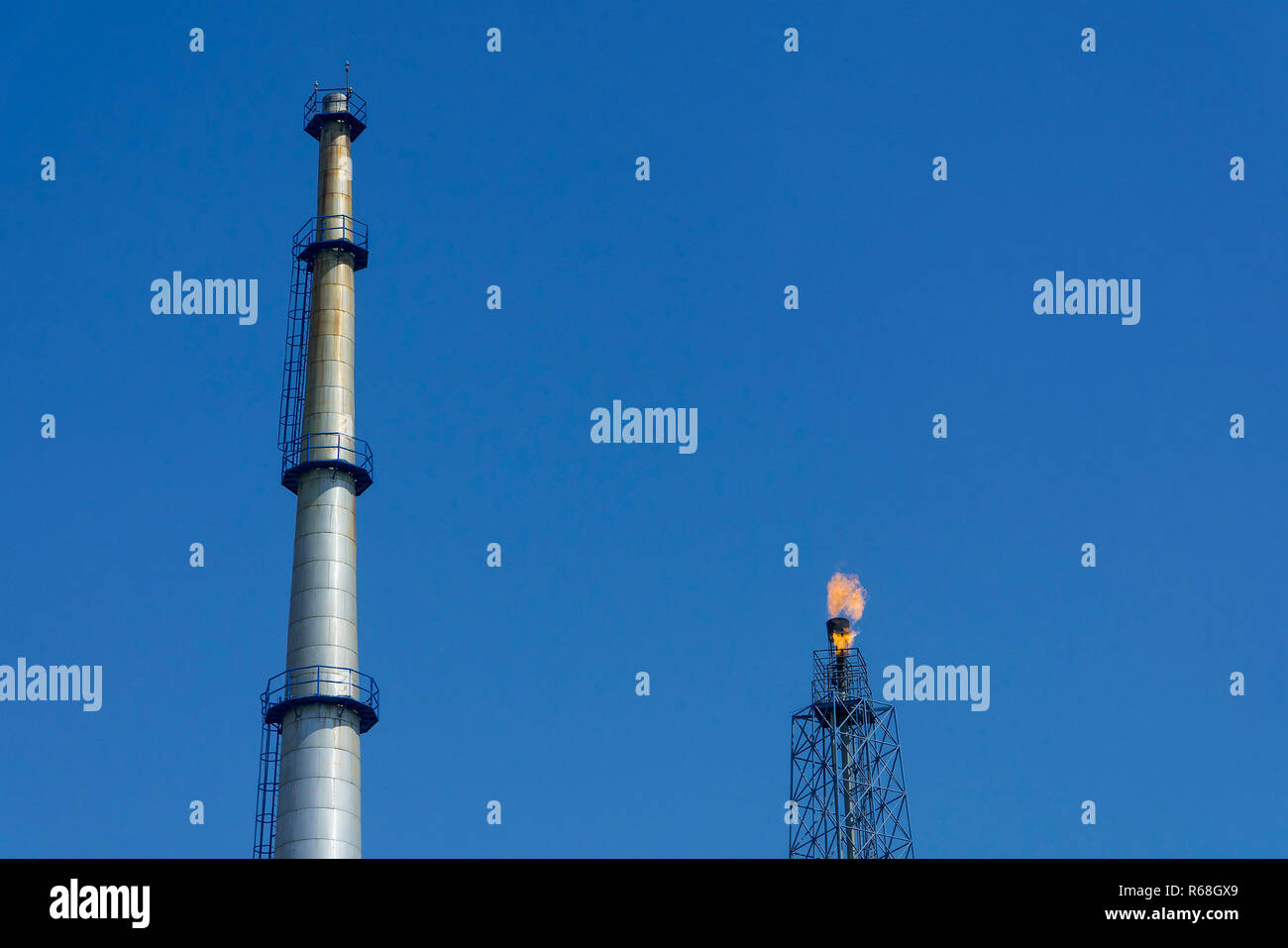 Gas flares in petroleum refinery with blue sky background Stock Photo ...