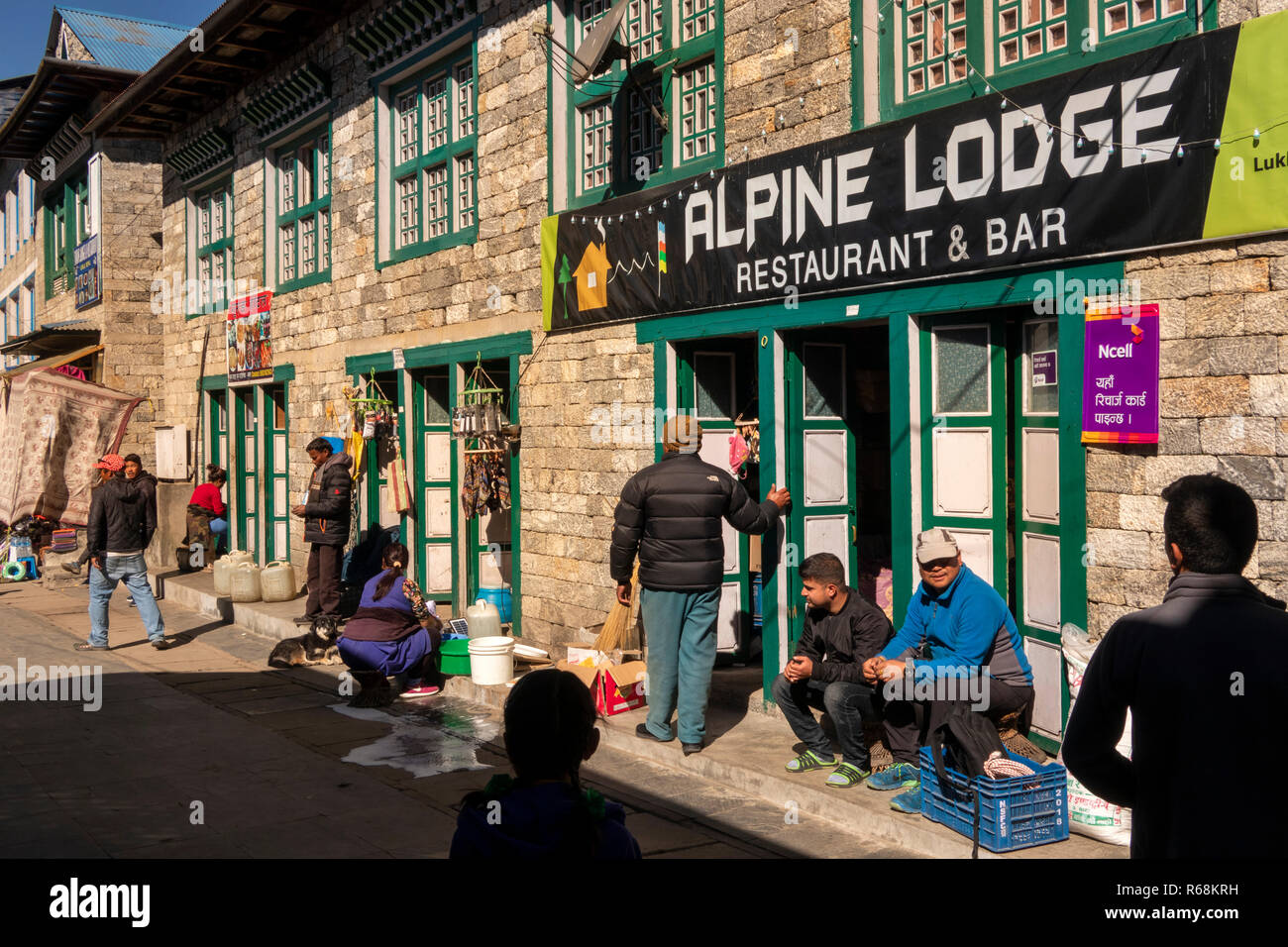 Nepal, Lukla, main street, people in sunshine outside Alpine Lodge ...