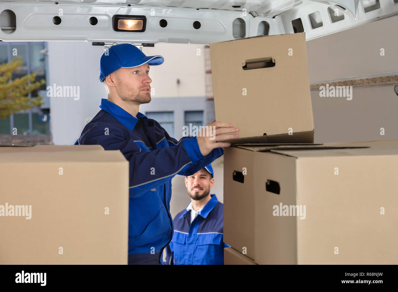 Mover Unloading Cardboard Box From Truck Stock Photo - Alamy