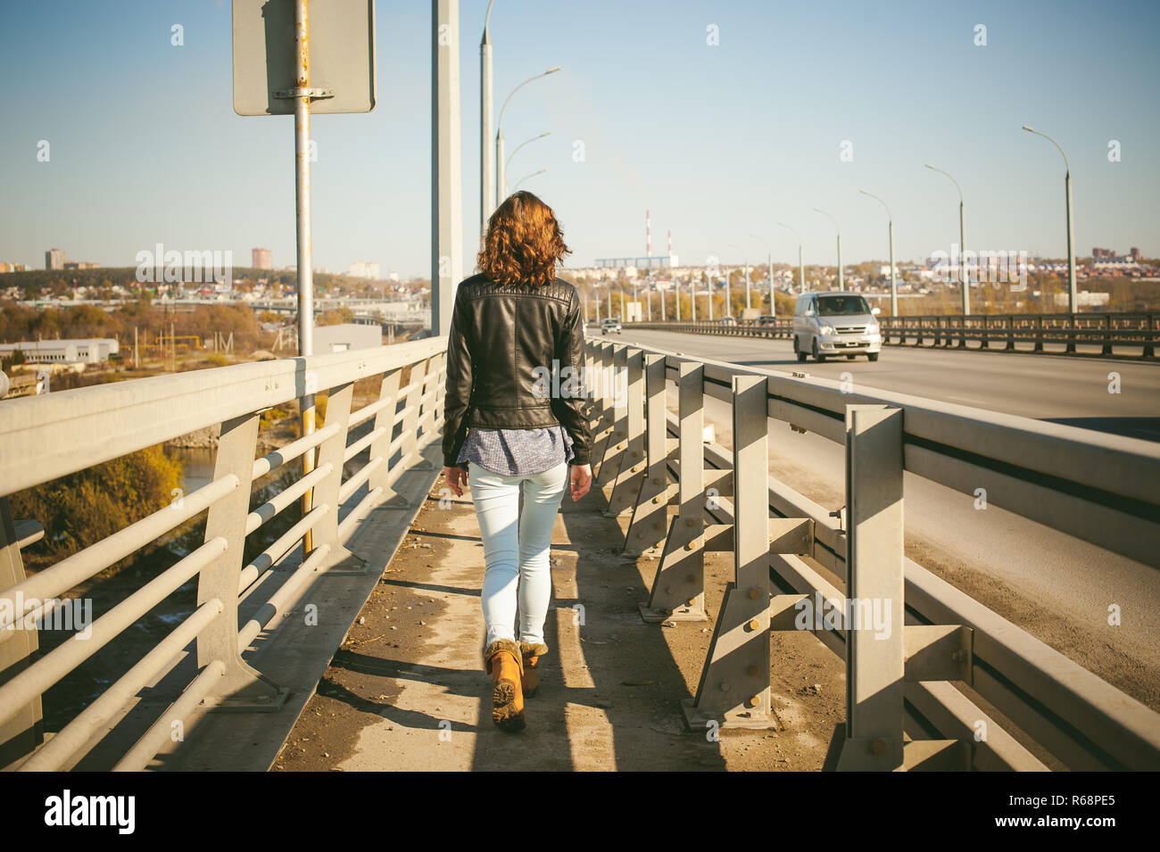 girl goes on road bridge. lonely young woman in black Leather jacket ...