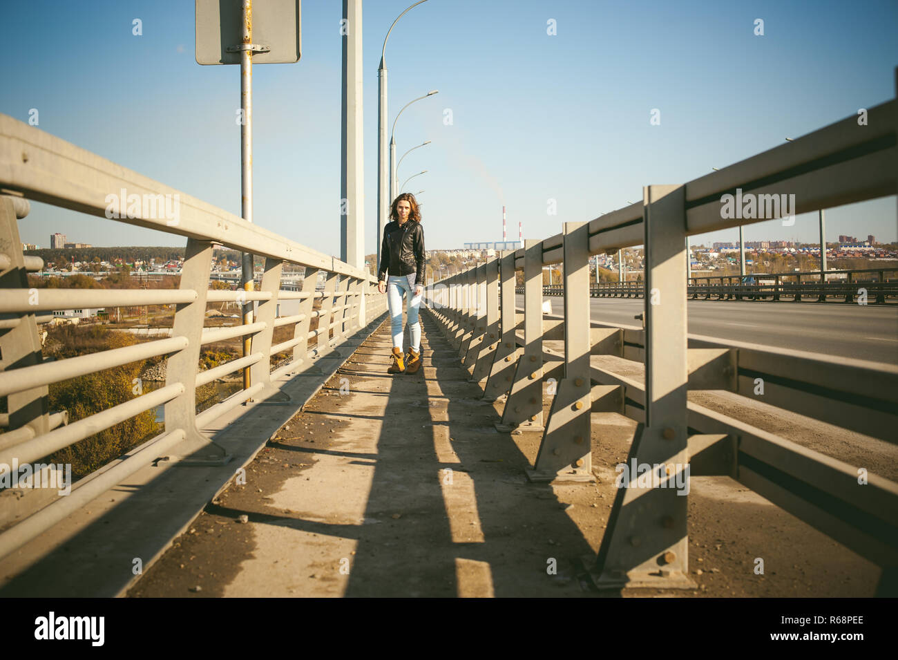 girl goes on road bridge. lonely young woman in black Leather jacket ...