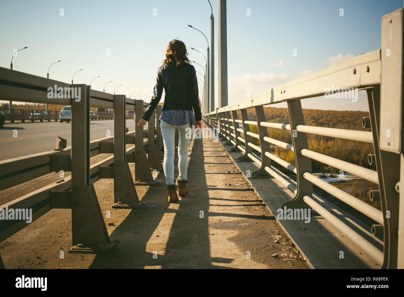 girl goes on road bridge. lonely young woman in black Leather jacket ...