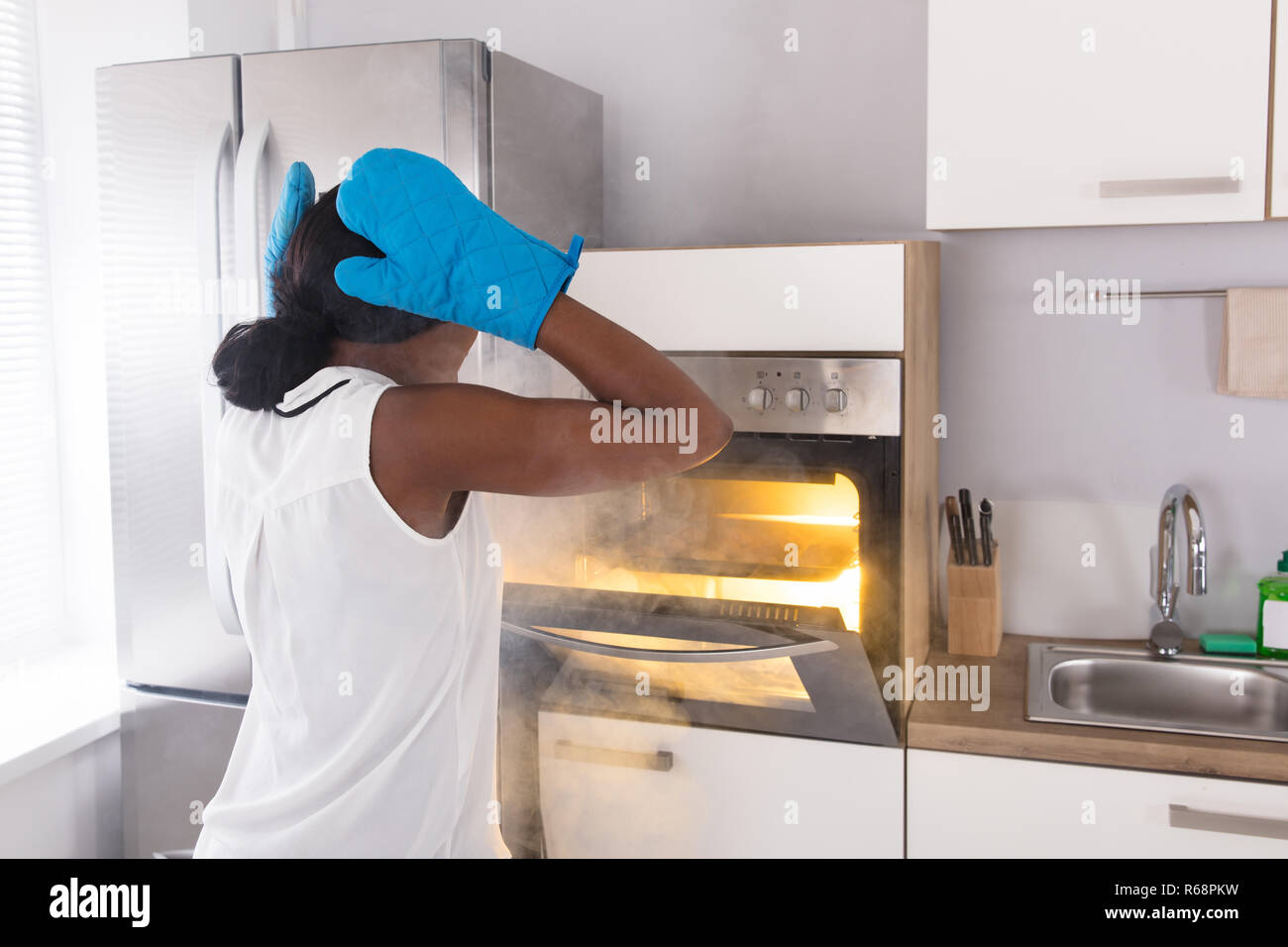 Shocked Woman Looking At Burnt Cookies In Oven Stock Photo - Alamy