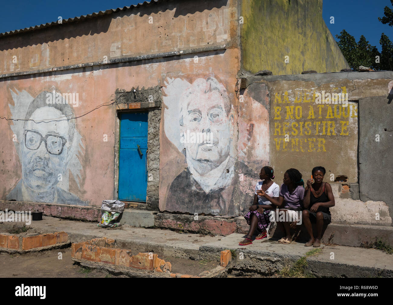 Young women in front of her house with an old Communist propaganda wall ...