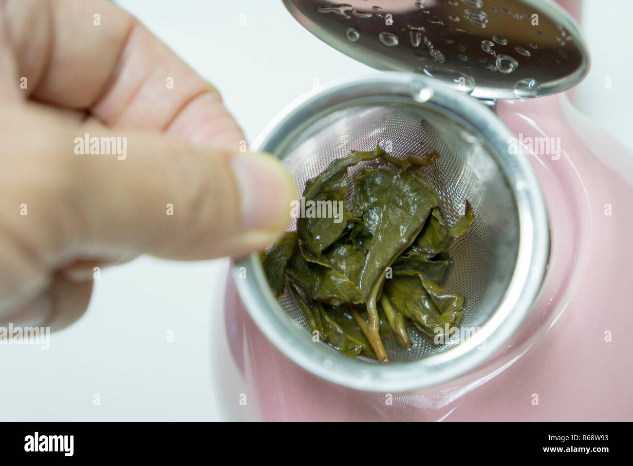 Used tea leaves in the kettle and hands Stock Photo - Alamy