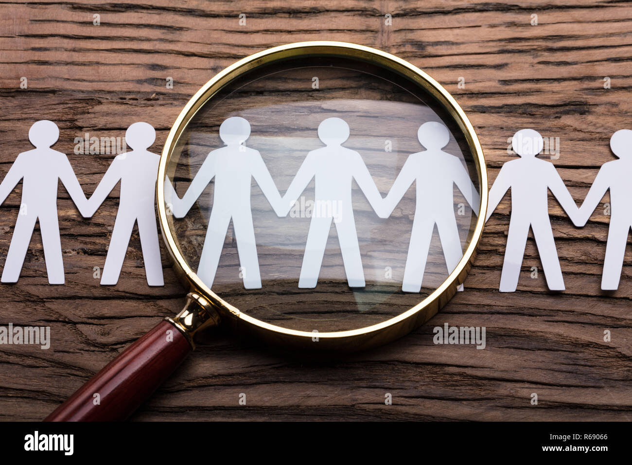 Magnifying Glass On Cut-out Figures Stock Photo - Alamy