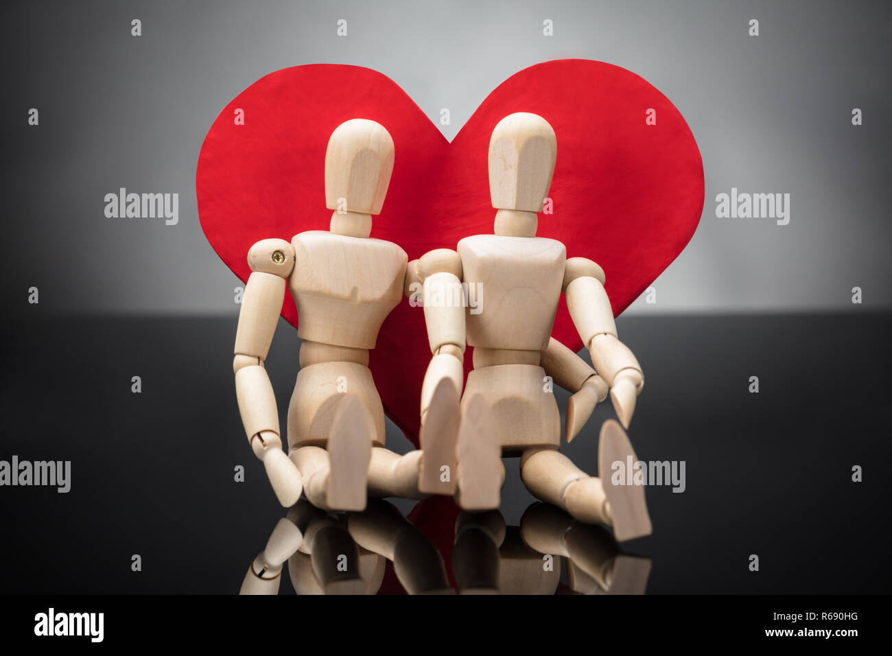 Wooden Dummy Couple Leaning On Heart Shape Stock Photo - Alamy