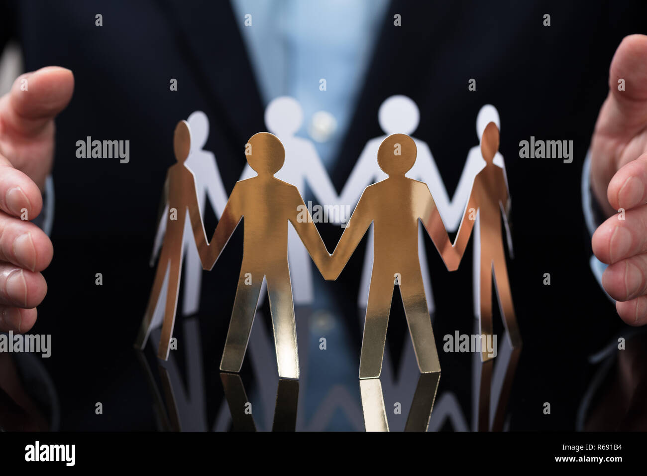 Businessperson Protecting Paper Cut Out People Stock Photo - Alamy