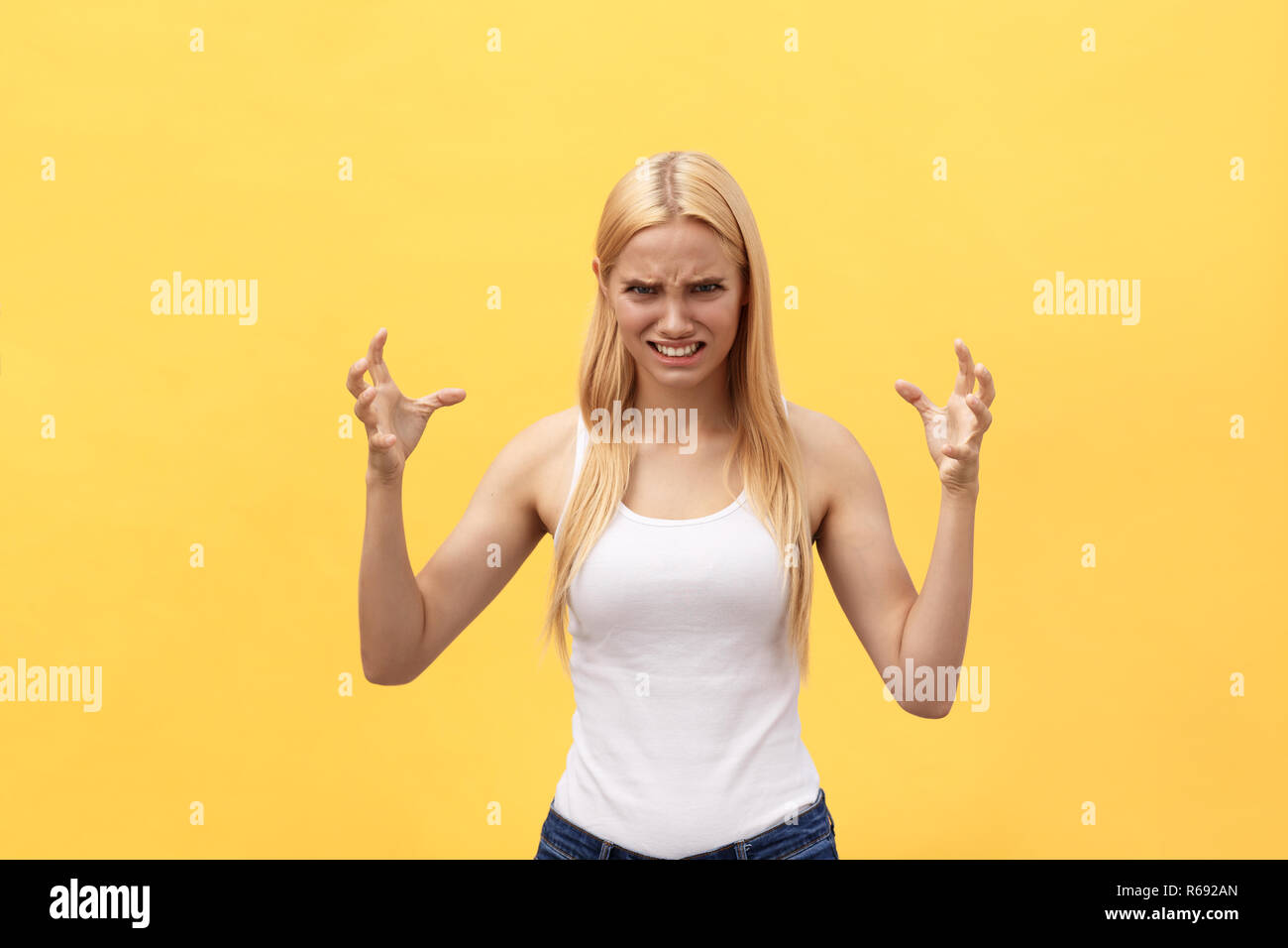 Portrait of an angry irritated woman with hands raised shouting at ...