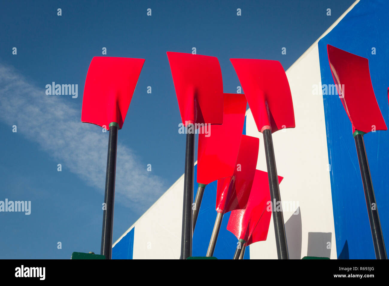 Colourful red oar blades by the blue and white boat tents against a ...
