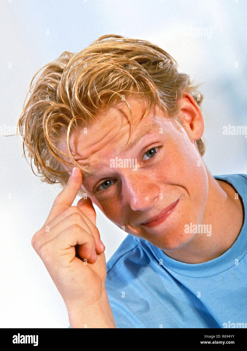 Portrait, Indoor, Junge mit kurzen rotblondem lockigen Haar tippt sich ...
