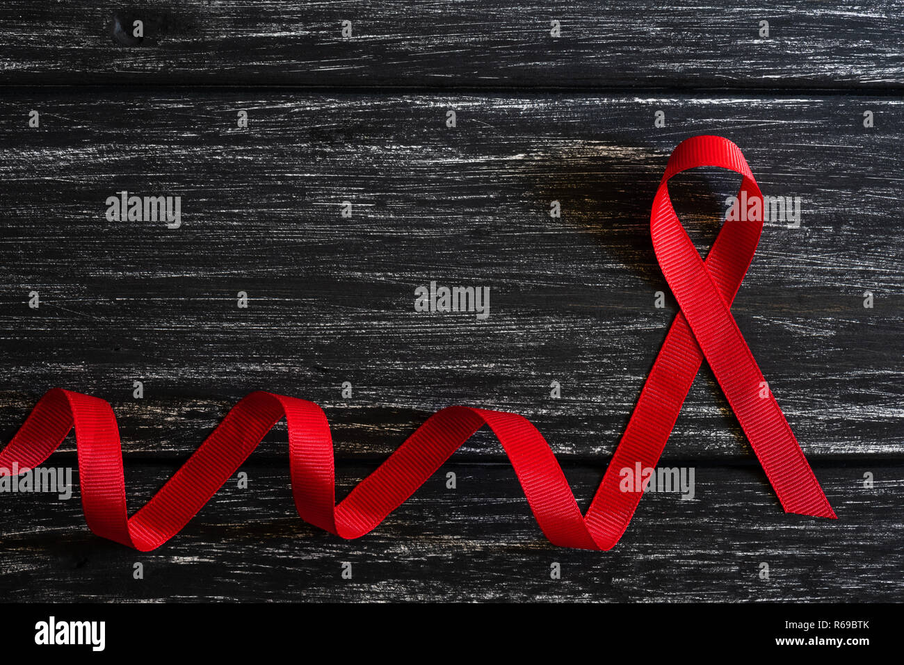 Closeup red ribbon awareness on black wooden table background for World ...