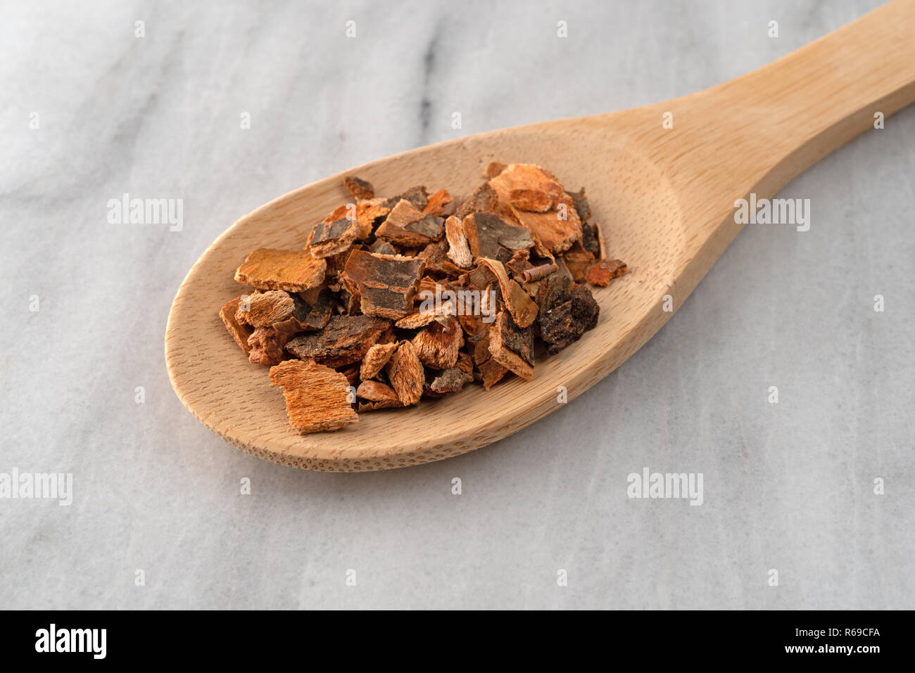 Small portion of wild cut cherry tree bark on a wood spoon atop a gray ...