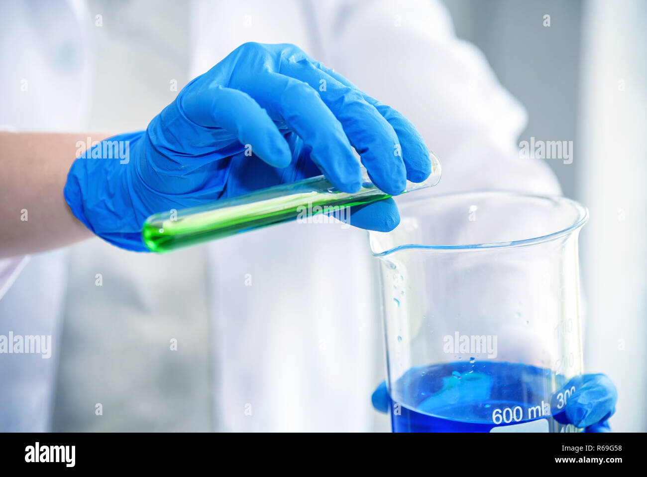 science laboratory researcher perform test with blue and green solution ...
