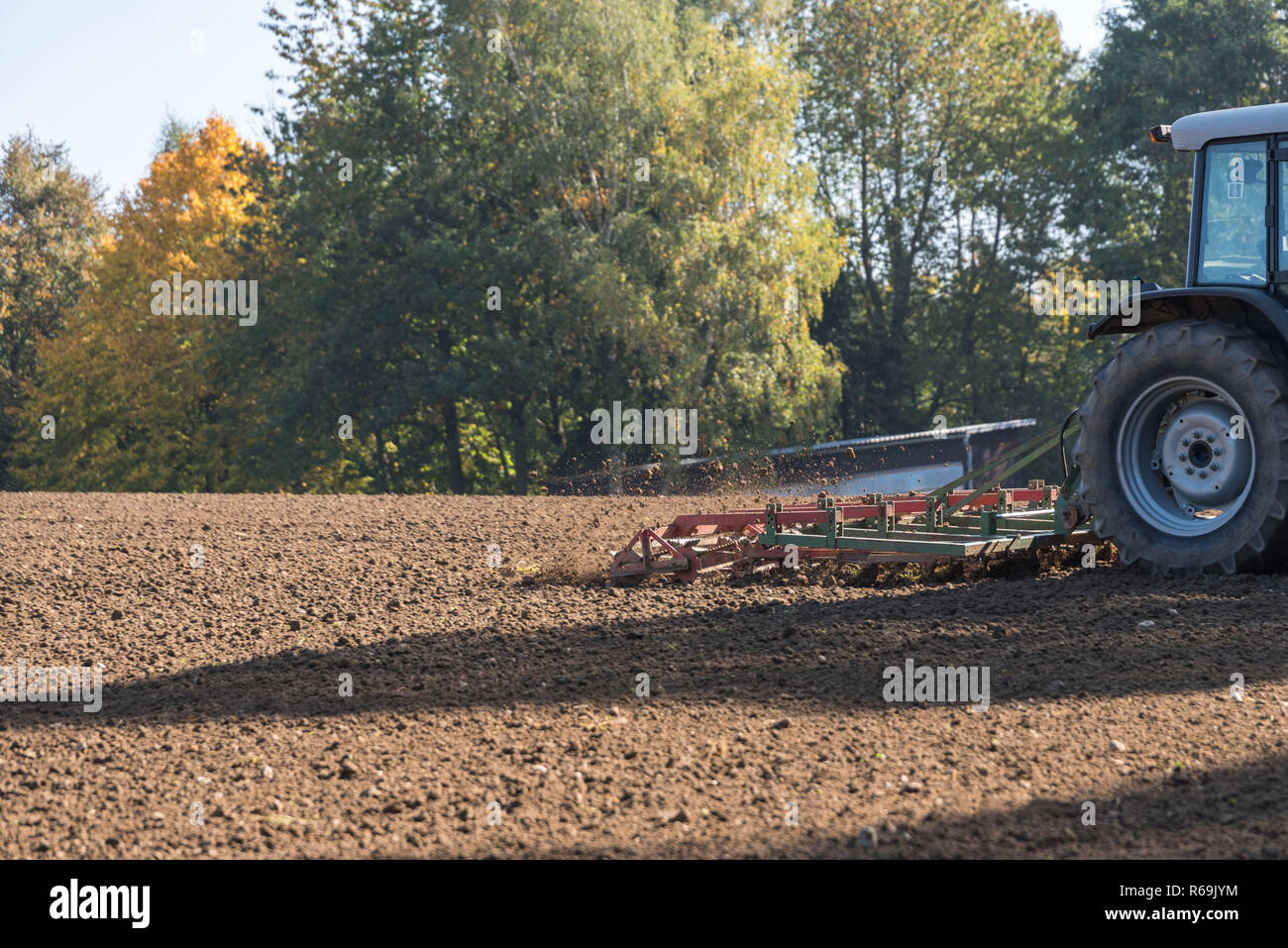 Farmer Works With Tractor And Harrow On The Farmland Stock Photo - Alamy