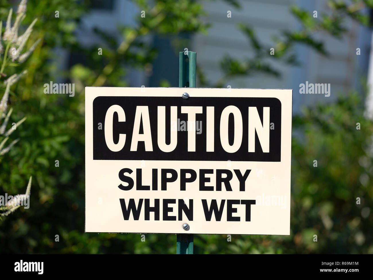 A caution slippery when wet sign on a metal post outside a business ...