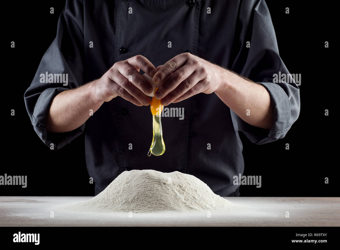 Falling eggs into flour. Hands breaking cracking a raw egg over flour ...