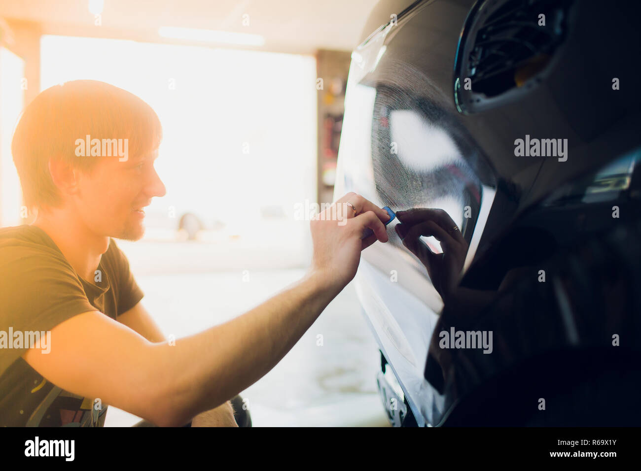 Worker hands installs car paint protection film wrap Stock Photo - Alamy