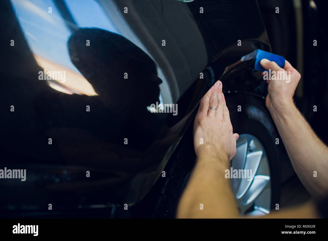 Worker hands installs car paint protection film wrap Stock Photo - Alamy