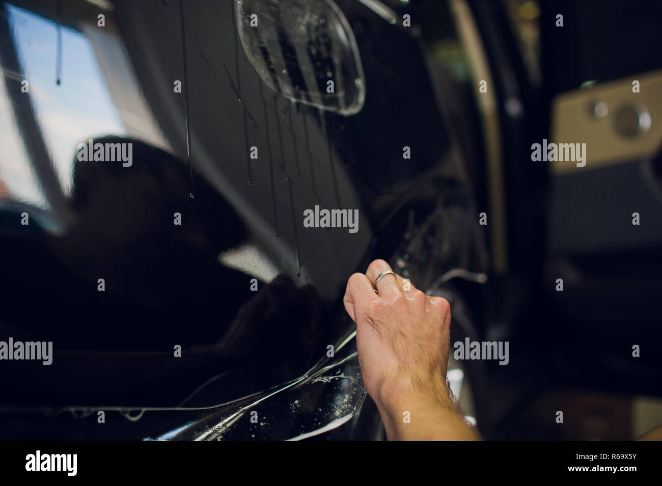 Worker hands installs car paint protection film wrap Stock Photo - Alamy