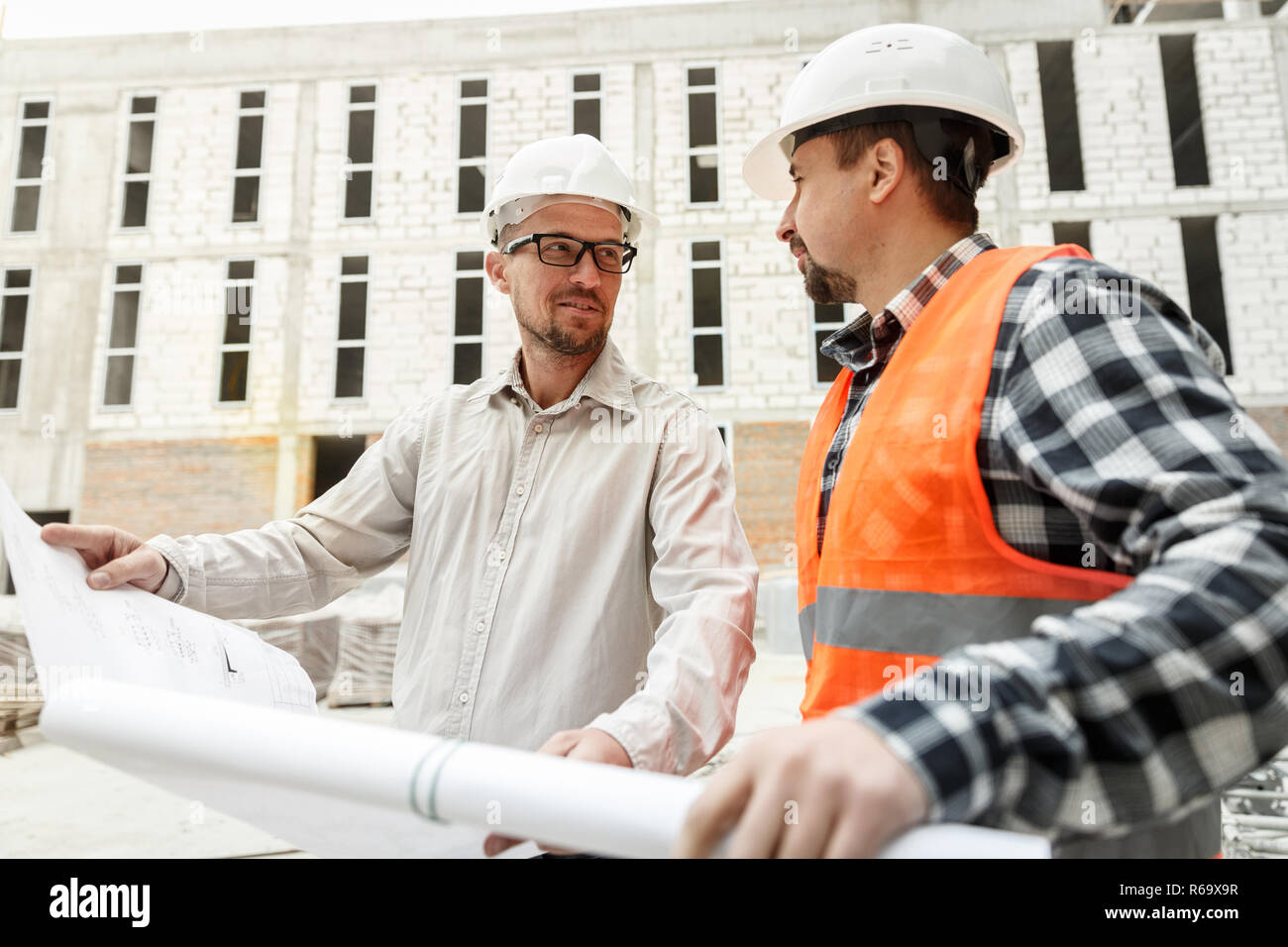 Male architect and developer with blueprints discussing architect ...