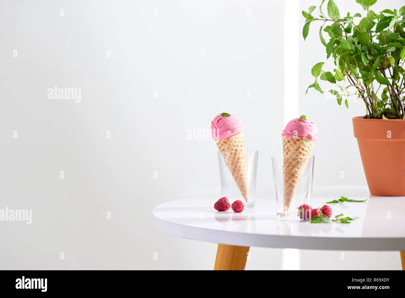Waffle cone filled with fresh raspberry ice cream in glass cup with ...