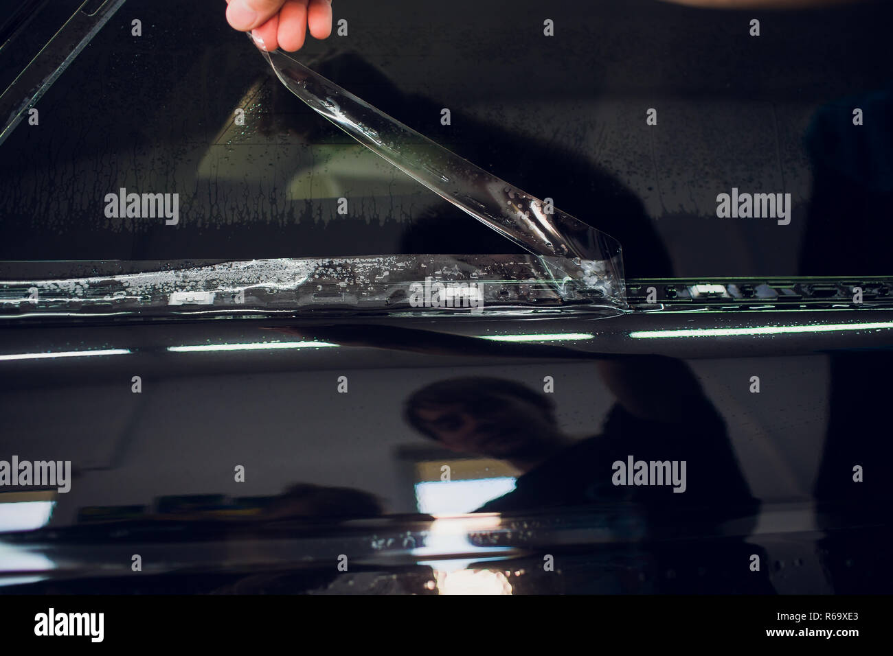 Worker hands installs car paint protection film wrap Stock Photo - Alamy