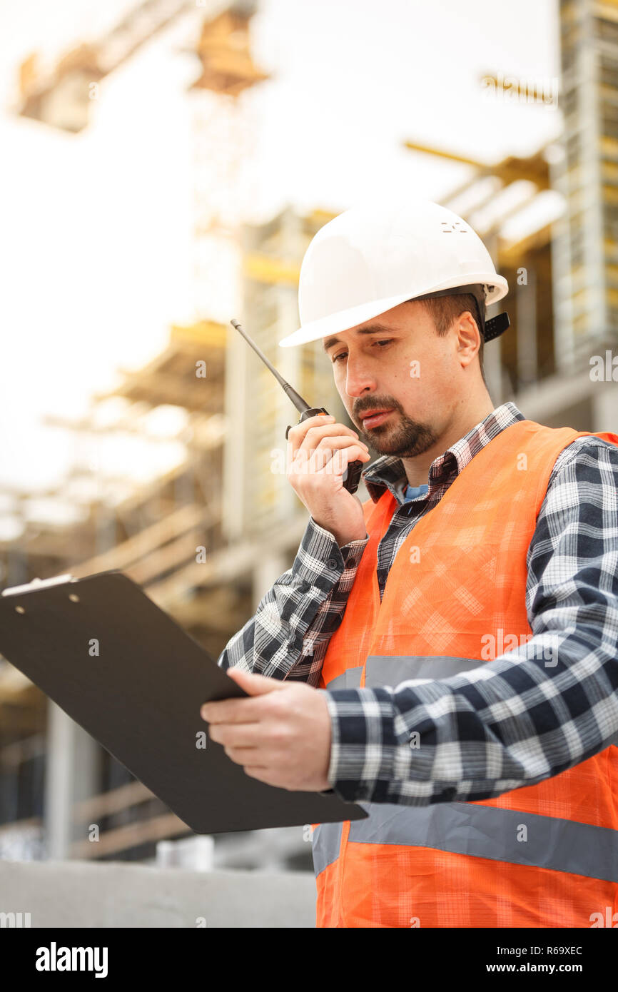 Developing engineer wearing white safety vest and hardhat with walkie ...