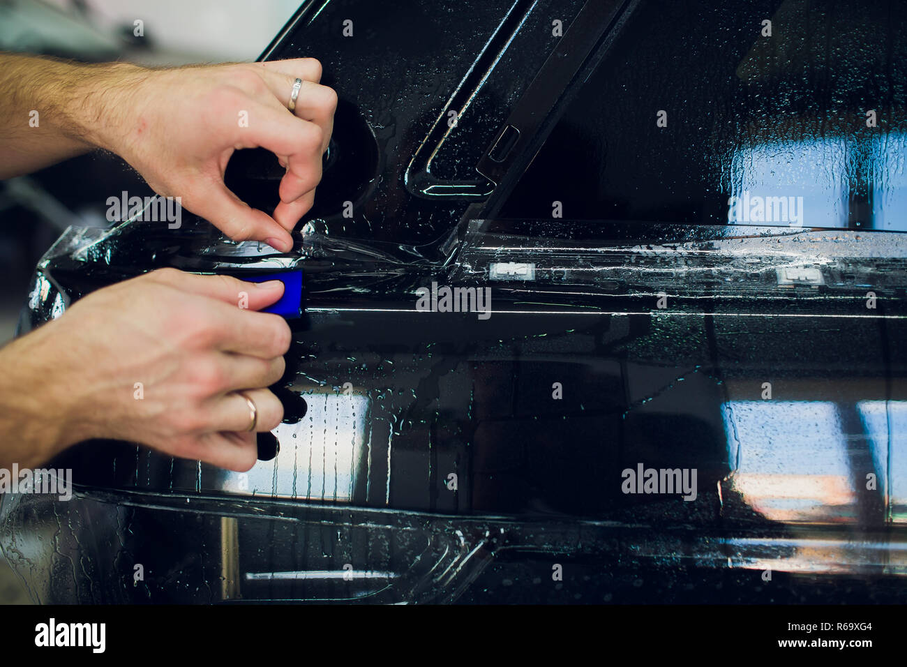Worker hands installs car paint protection film wrap Stock Photo - Alamy