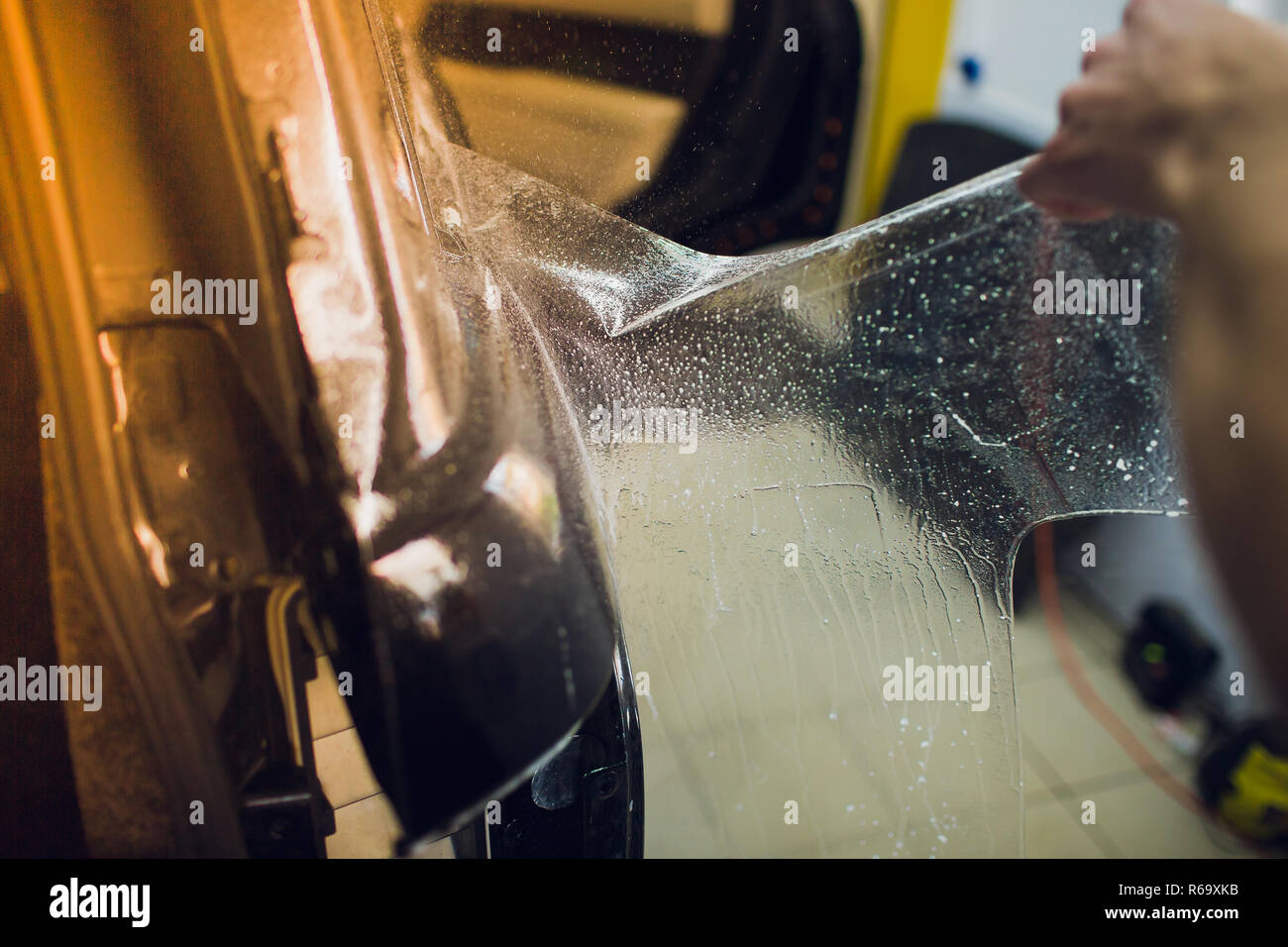 Worker hands installs car paint protection film wrap Stock Photo - Alamy
