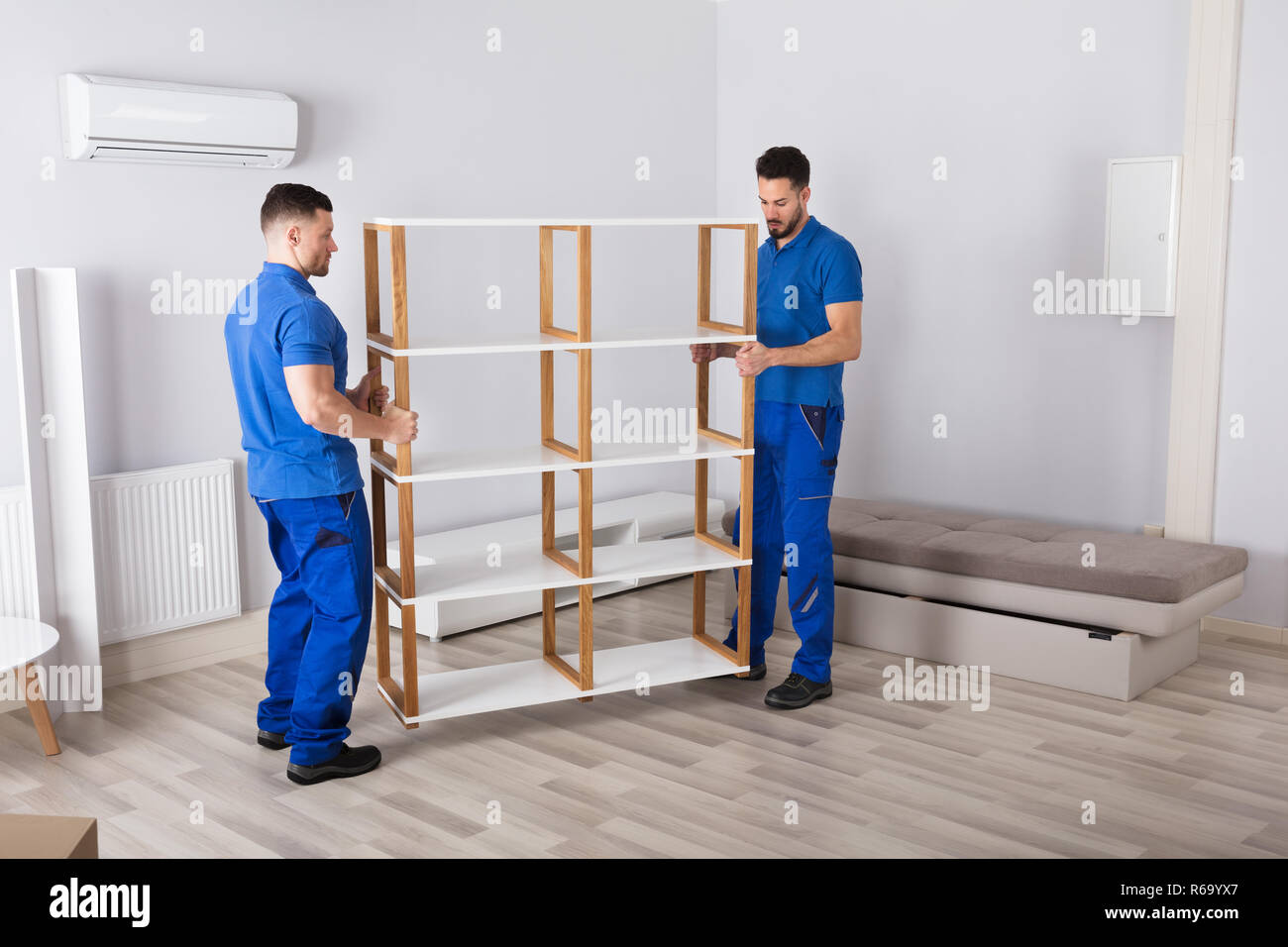 Two Men Holding Shelf In Living Room Stock Photo - Alamy