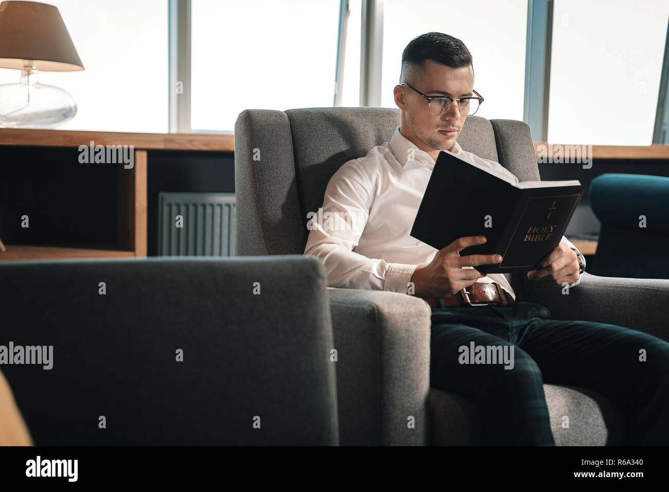 Smart young man wearing glasses reading the Holy Bible Stock Photo - Alamy