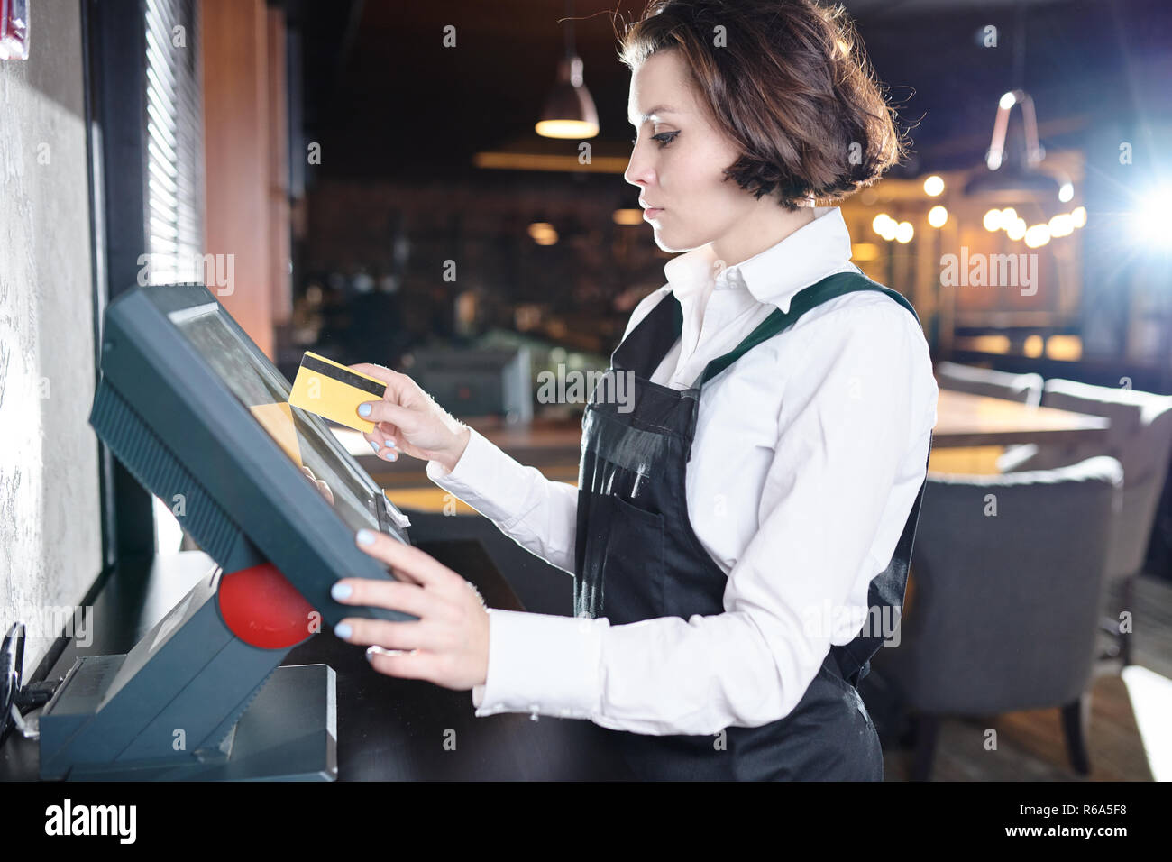 Serious concentrated young waitress with short hair standing at ...