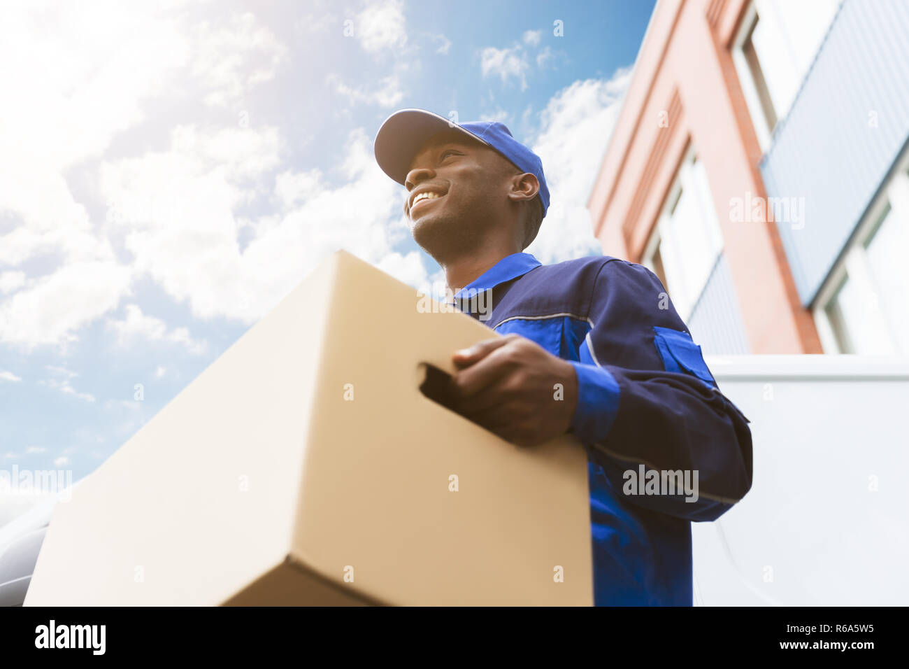 Loader Man With Cardboard Box Stock Photo - Alamy
