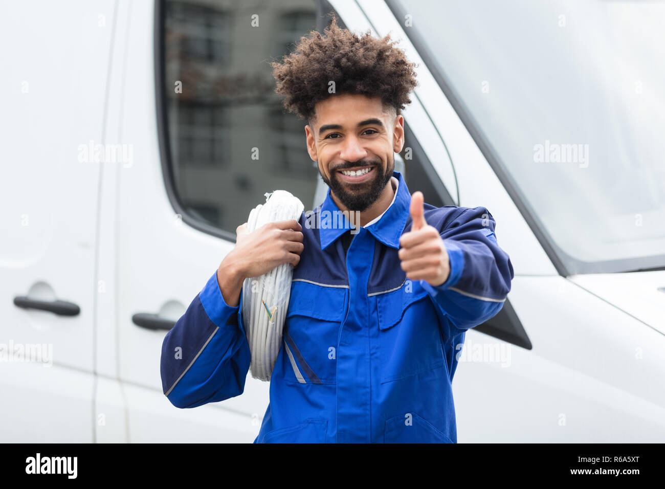 Smiling Electrician With White Cable Coil Stock Photo - Alamy