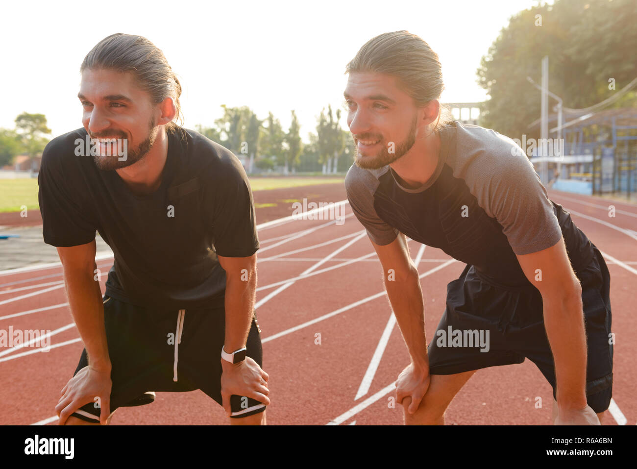 Photo of young two twins sportsmen brothers standing at the stadium ...