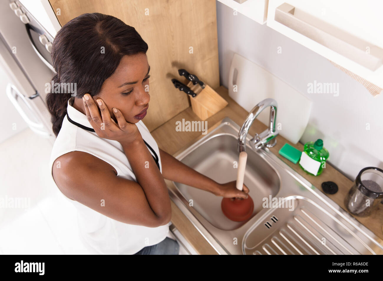 Unhappy Woman Using Plunger In Clogged Sink Stock Photo - Alamy