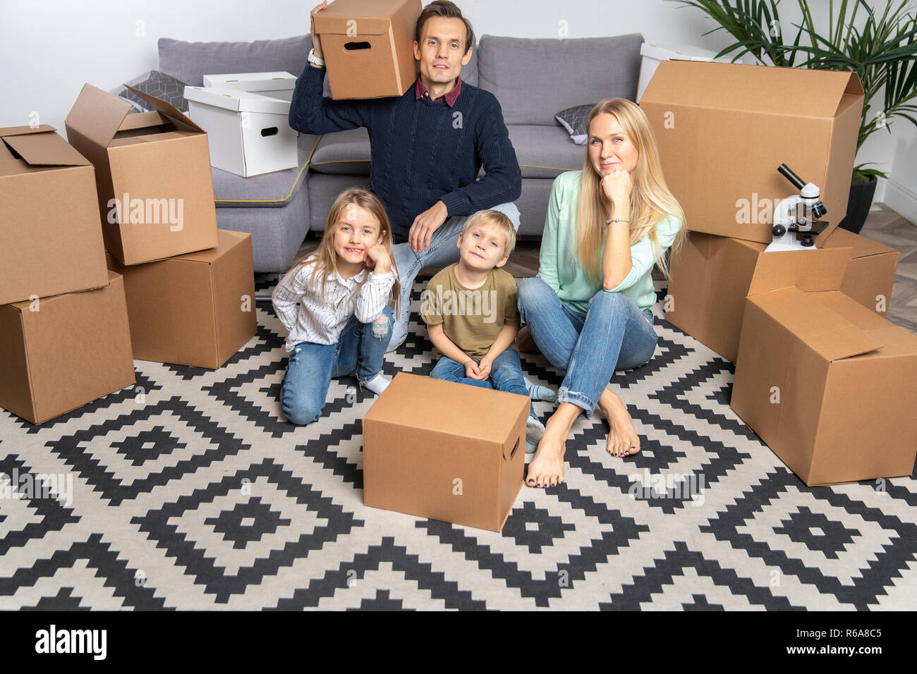 Photo from above parents and children among cardboard boxes sitting on ...