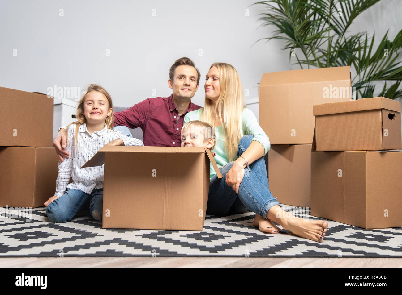 Photo of young parents and children among cardboard boxes sitting on ...