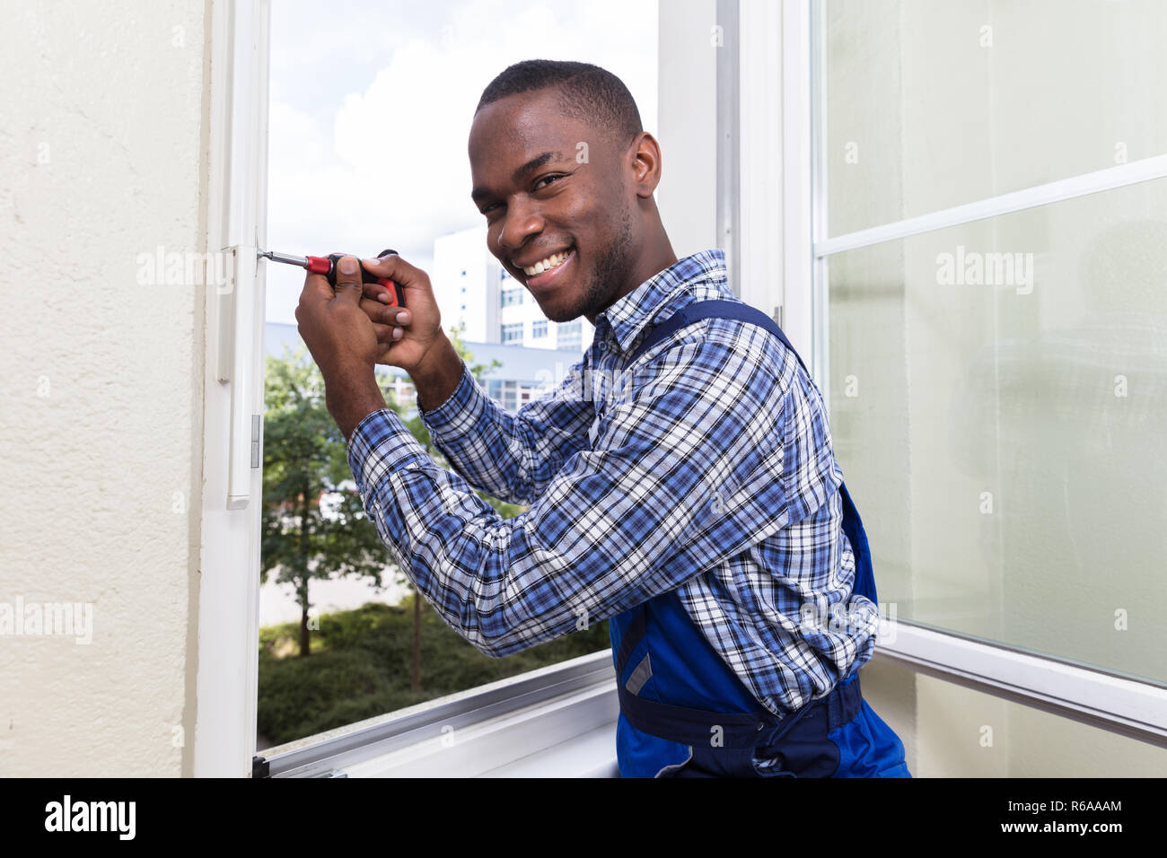 Handyman In Uniform Fixing Glass Window Stock Photo - Alamy