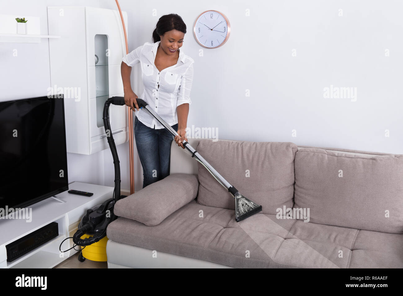 African Woman Cleaning Sofa With Vacuum Cleaner Stock Photo - Alamy